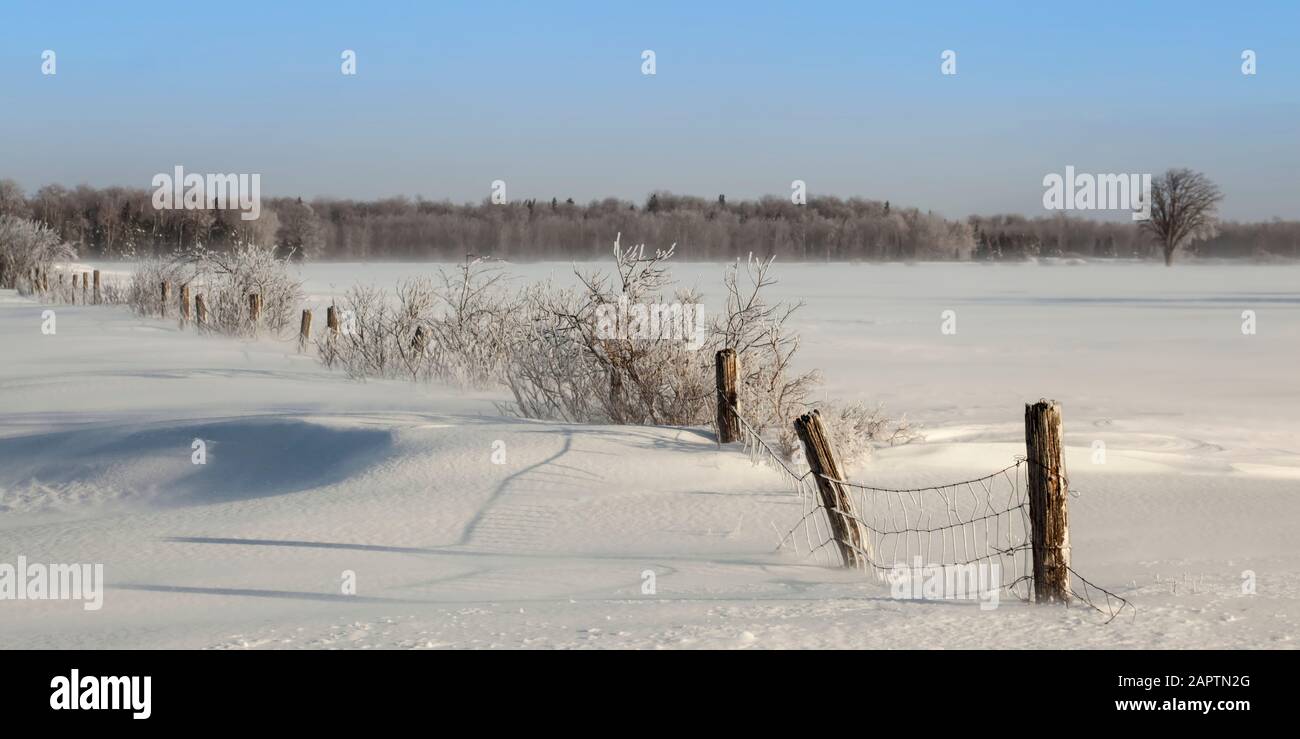 Winter landscape with snowy fields, fence and blue sky; Sault St. Marie ...