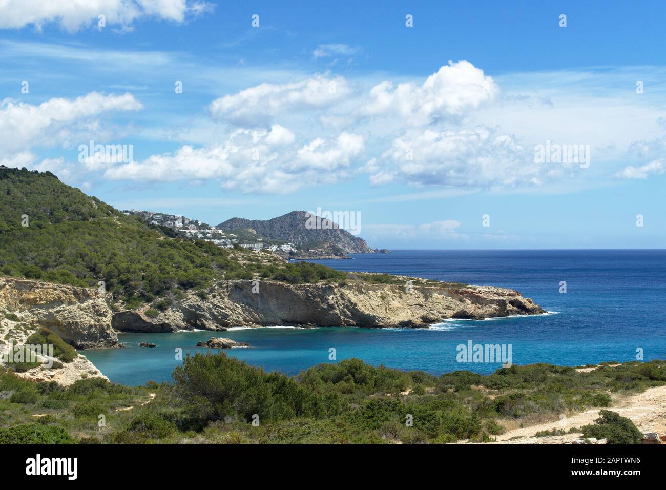 Rocky coast at the Balearic sea with vegetation, blue water and cloudy ...