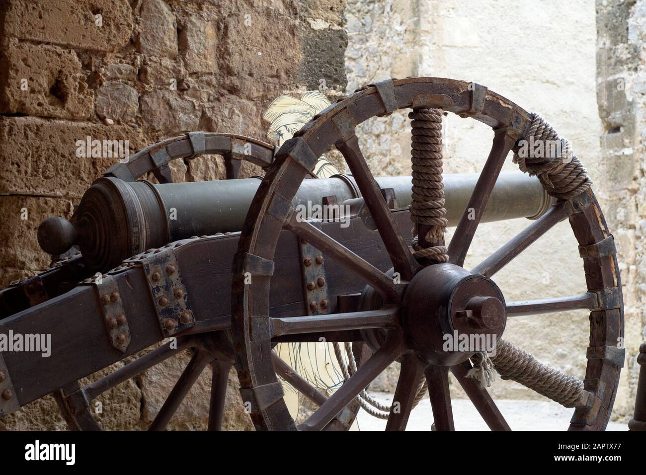 Medieval cannon in Ibiza castle with a merchant figure and brick walls ...