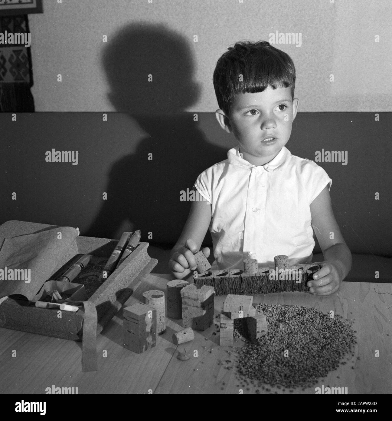 Boy plays with cork. Next to him cigars in a cigar box camouflaged as ...