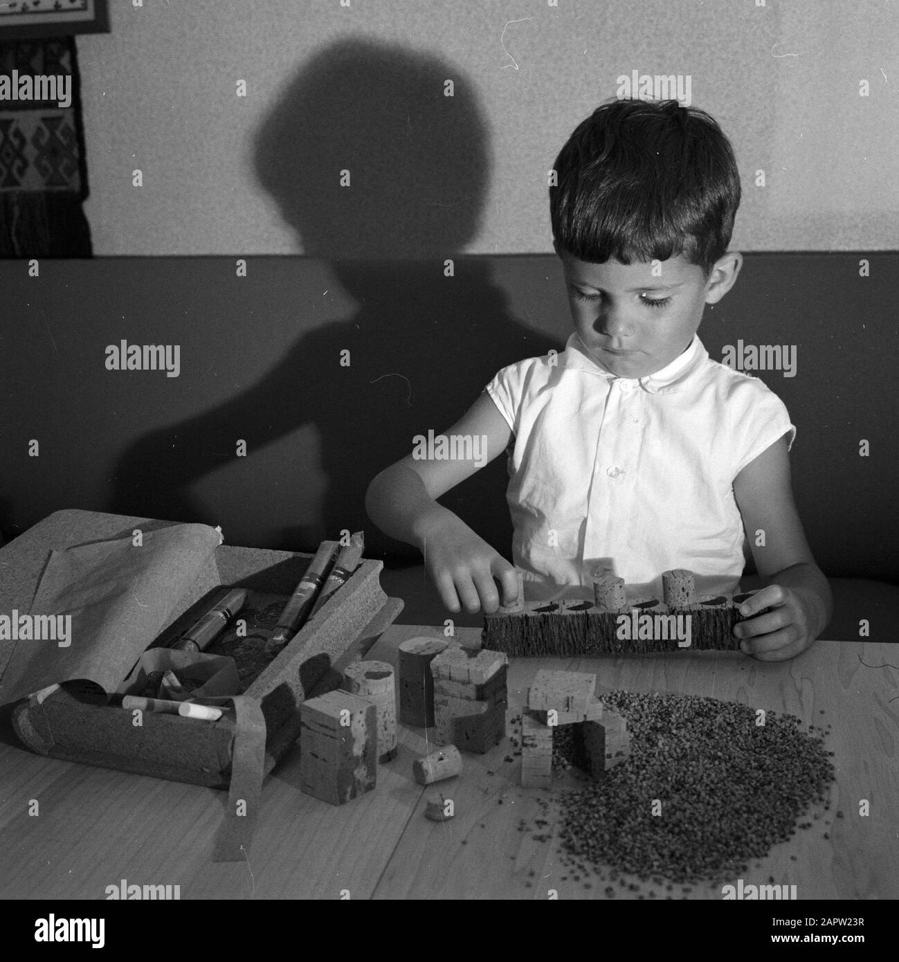 Boy plays with cork. Next to him cigars in a cigar box camouflaged as ...