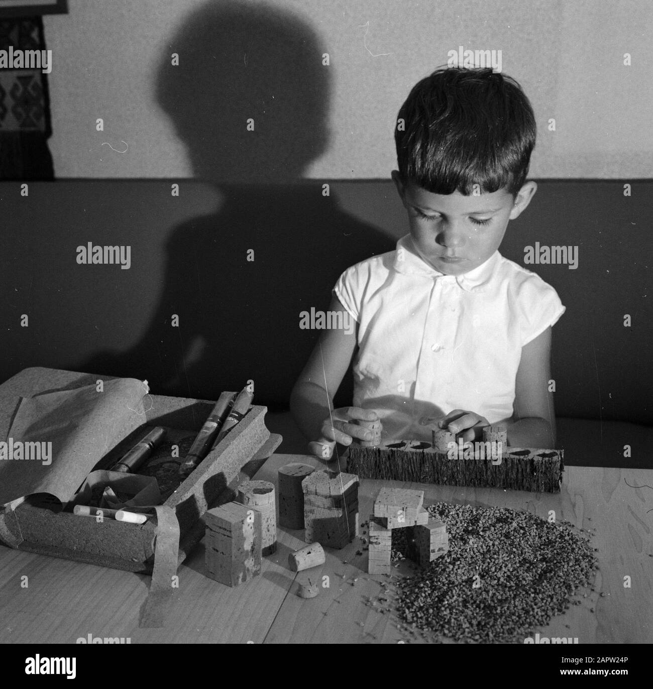 Boy plays with cork. Next to him cigars in a cigar box camouflaged as ...