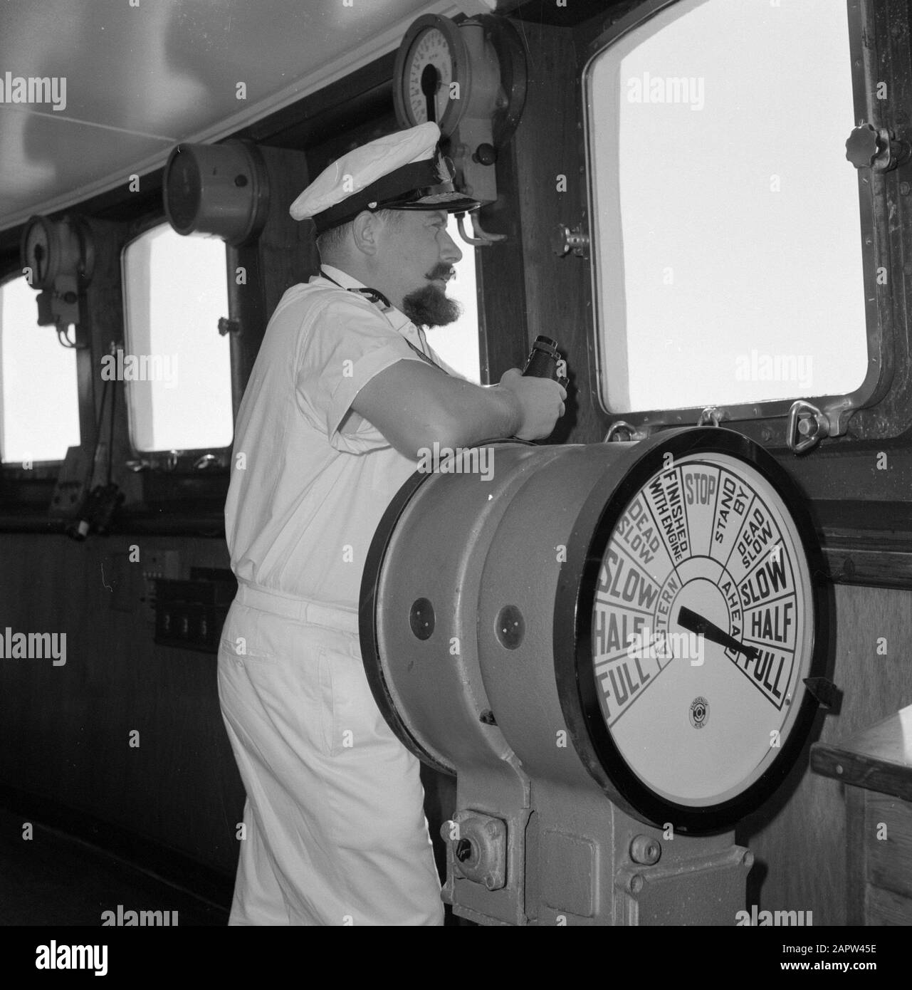 Captain in white uniform with binoculars in the wheelhouse standing by ...