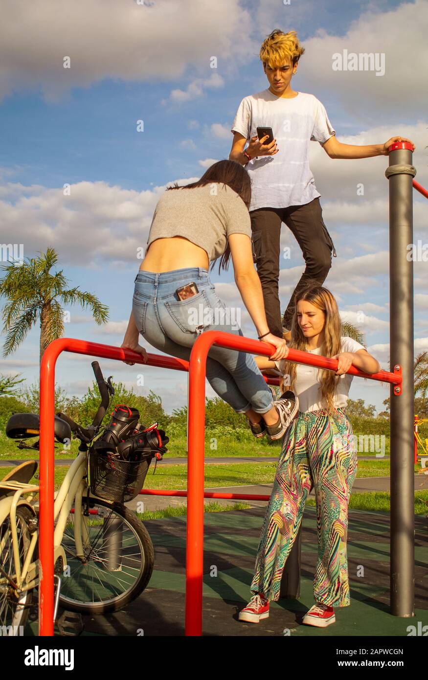 Two girls have fun at the parallel bars while a boy takes a picture of ...