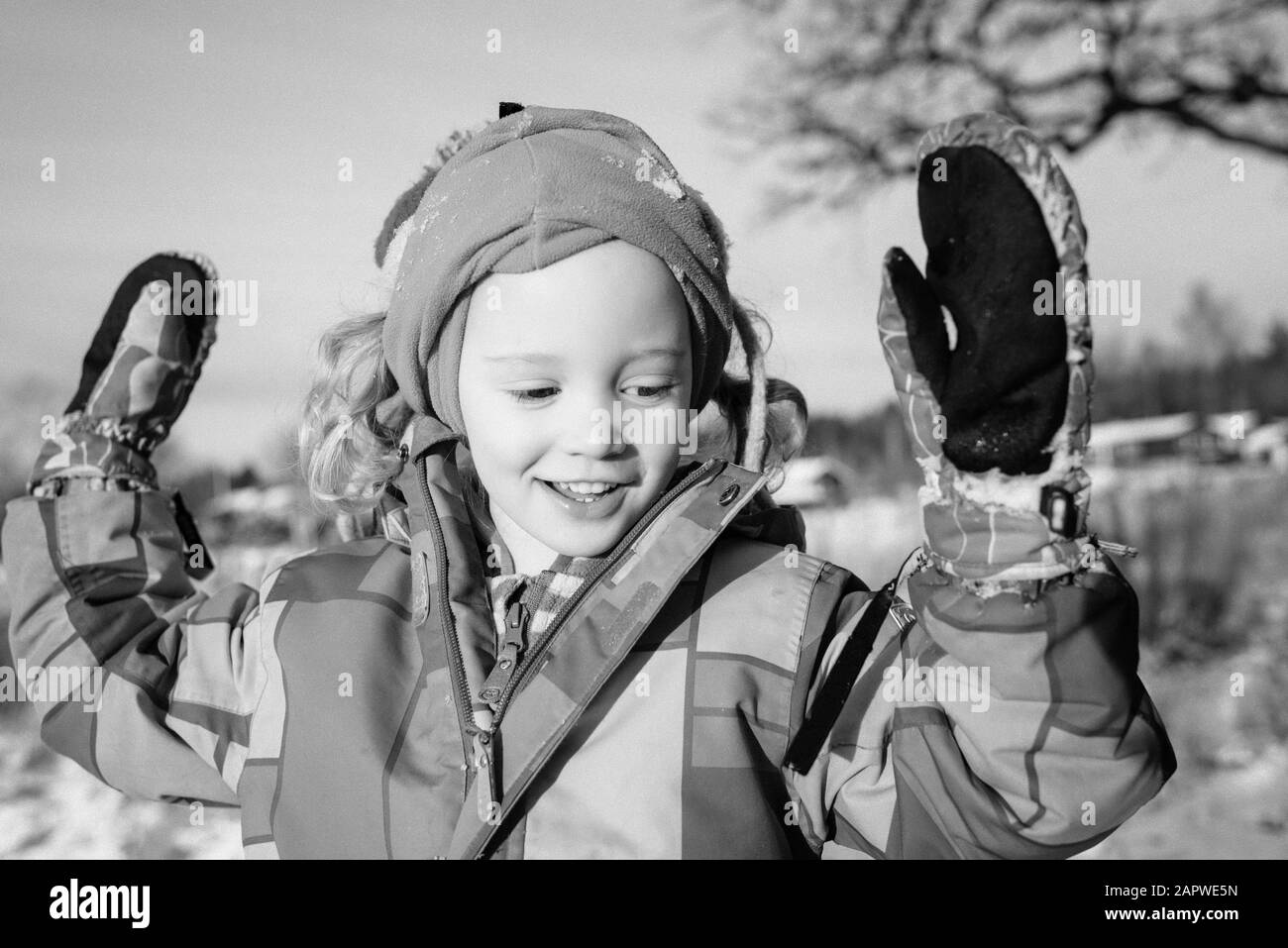 young girl stood with her hands up in the air whilst playing outside ...