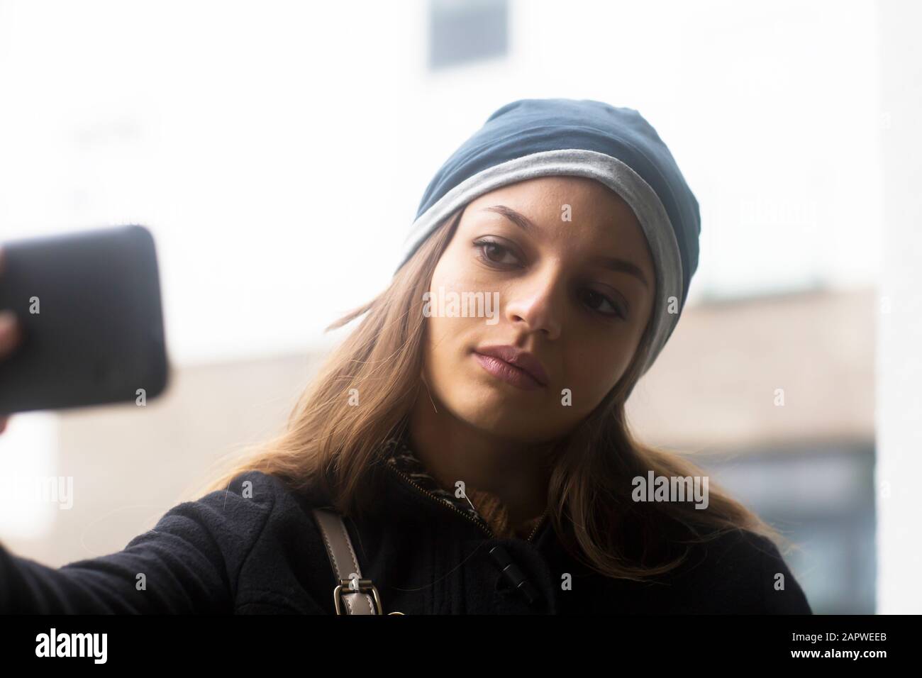 young woman with cap outside taking a selfie Stock Photo - Alamy