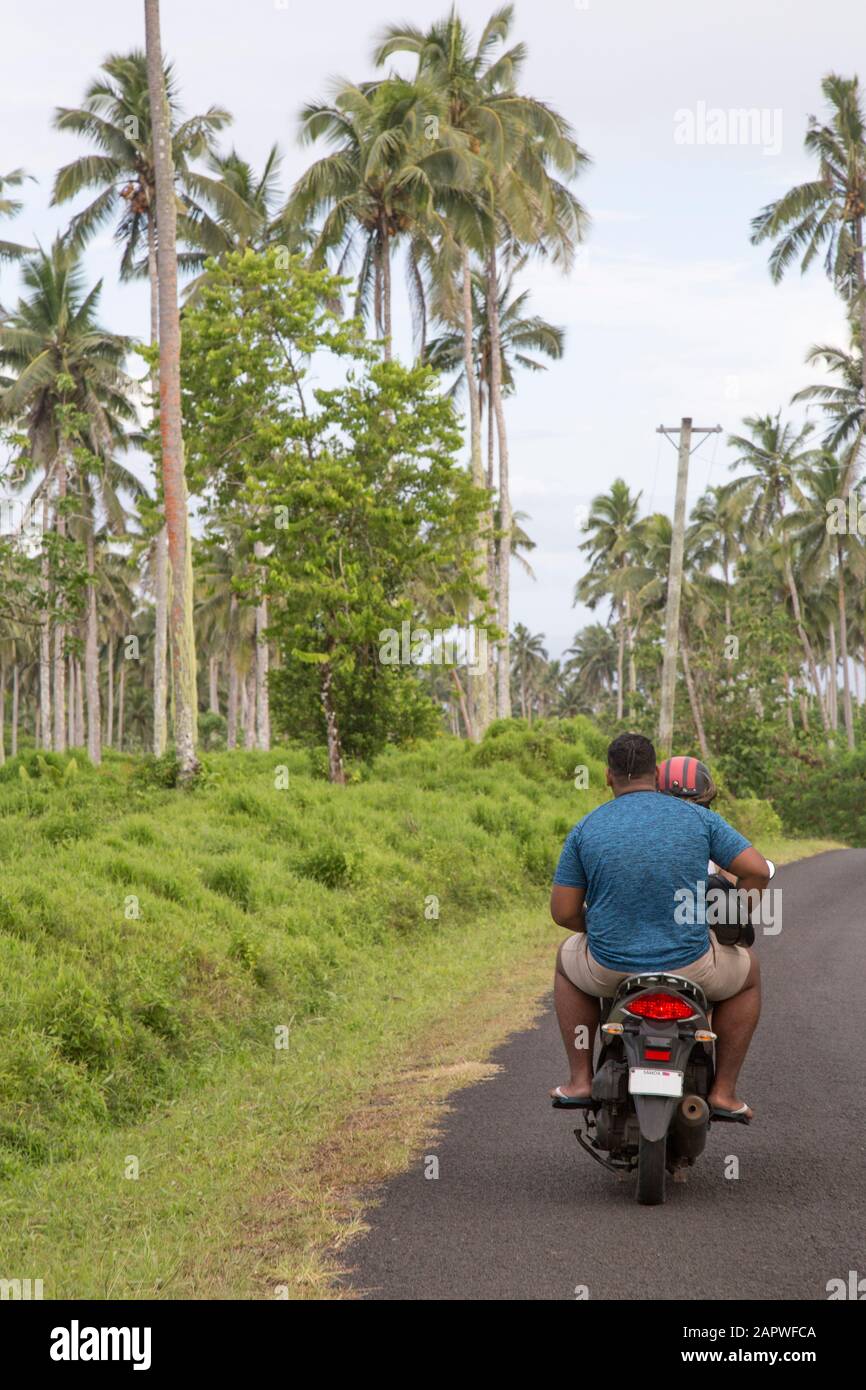 Two people riding a scooter across an exotic and tropical landscape ...