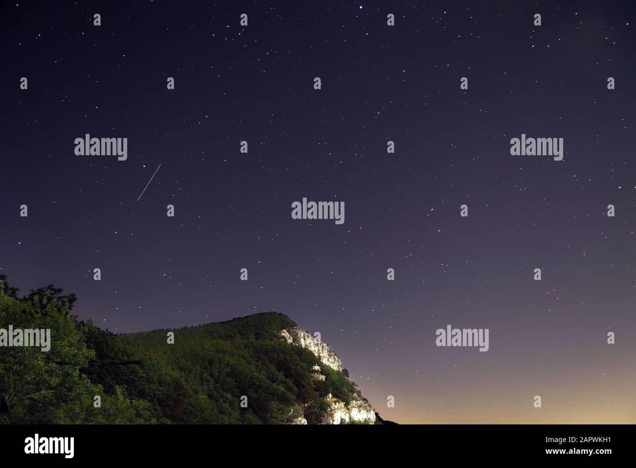 Beautiful shot of a mountain cliff with a starry night purple sky in ...