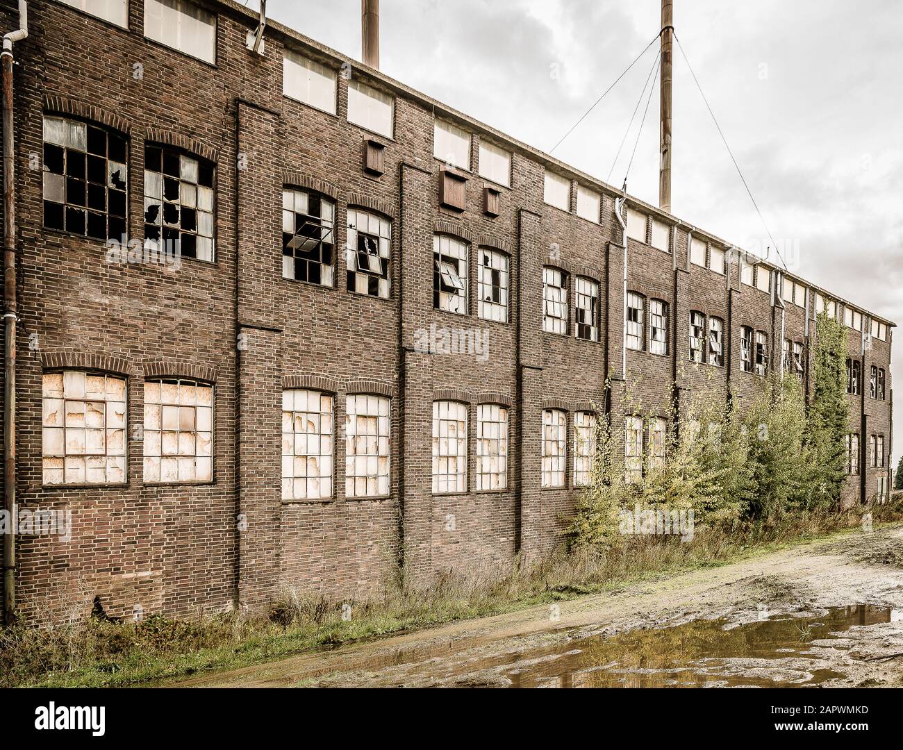 Old abandoned stone building with broken windows and a puddle outside ...