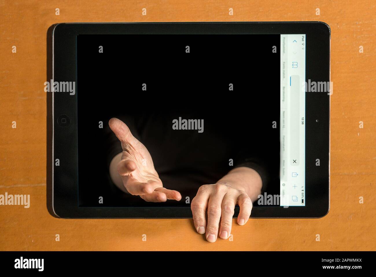 Illustration of a man's hands coming out of an iPad on a brown table ...