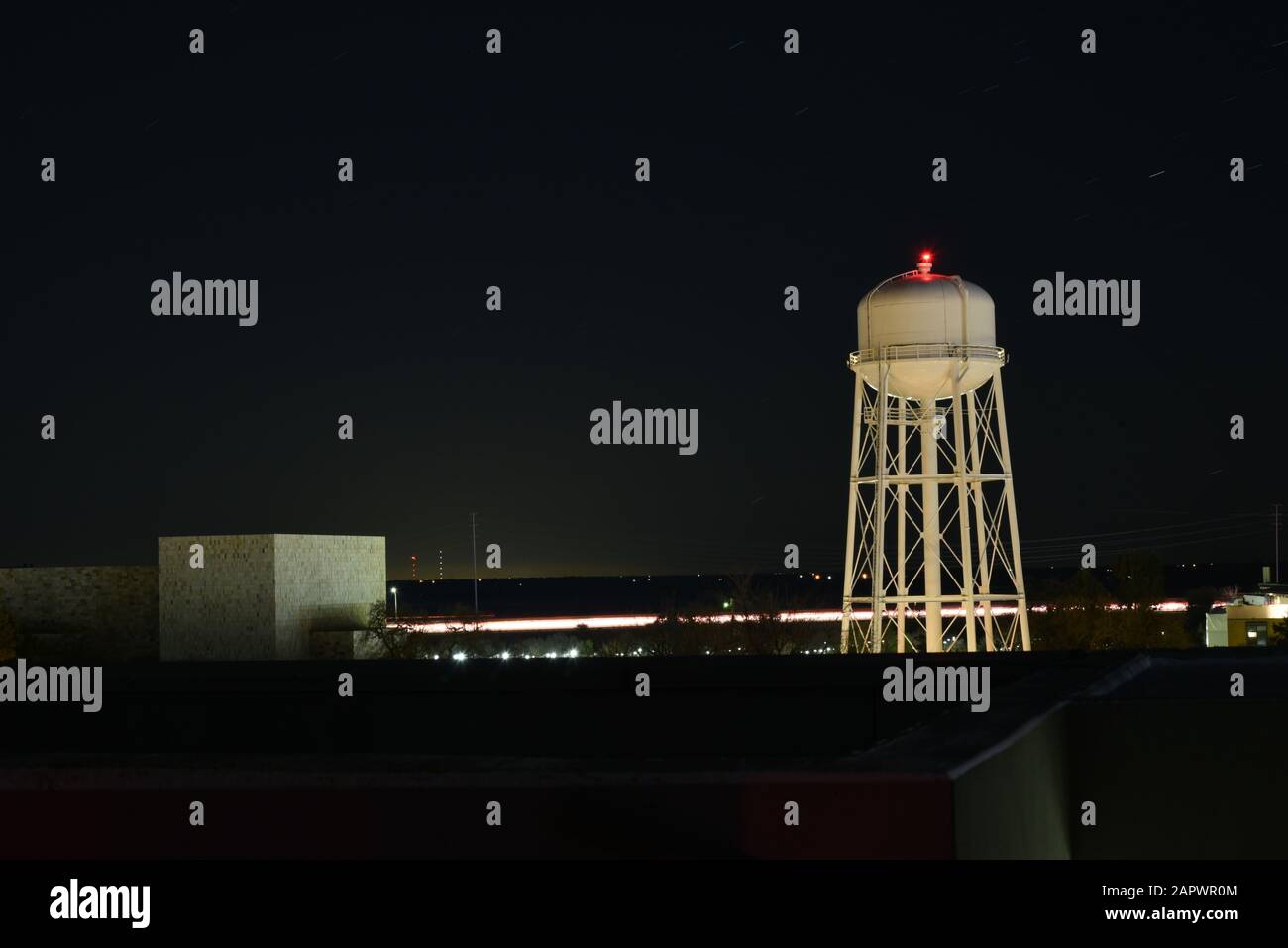 Metal water tower at night with a red beacon on top Stock Photo - Alamy