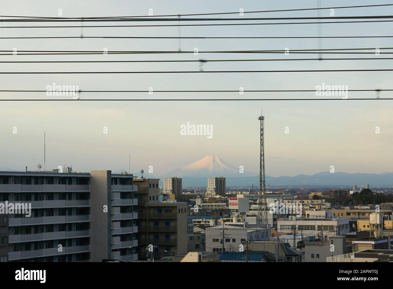 A snowy Mount Fuji (Mt. Fuji) towers in the distance over a city ...