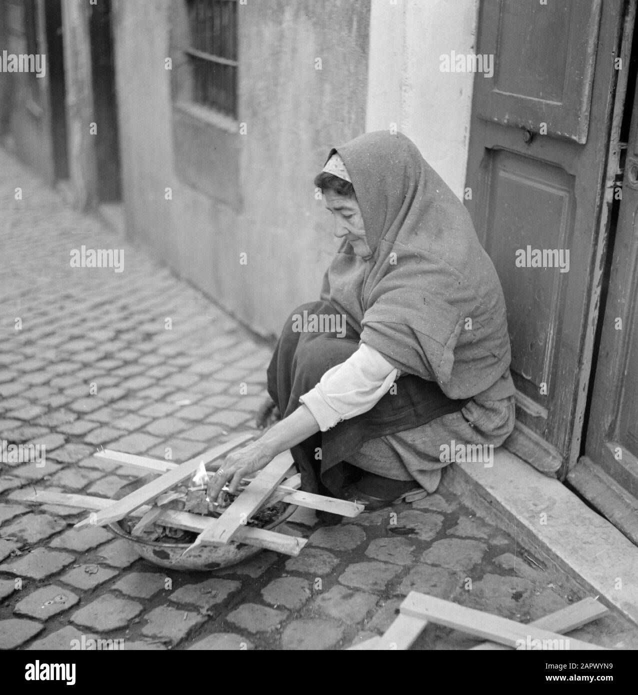 Rome: Visit to the city Old woman makes a fire Date: December 1937 ...