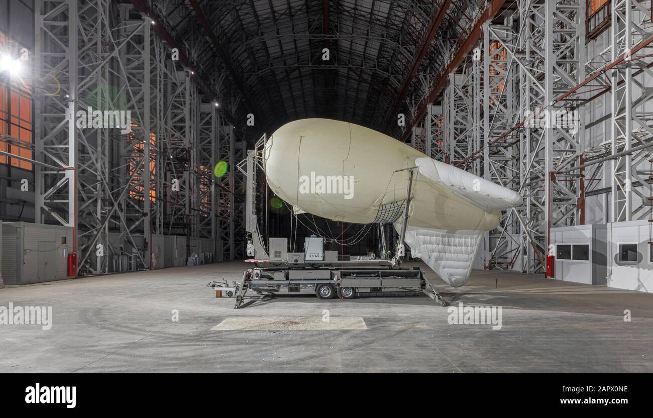 Small blimp on a mooring platform inside a giant airship hangar. Side ...