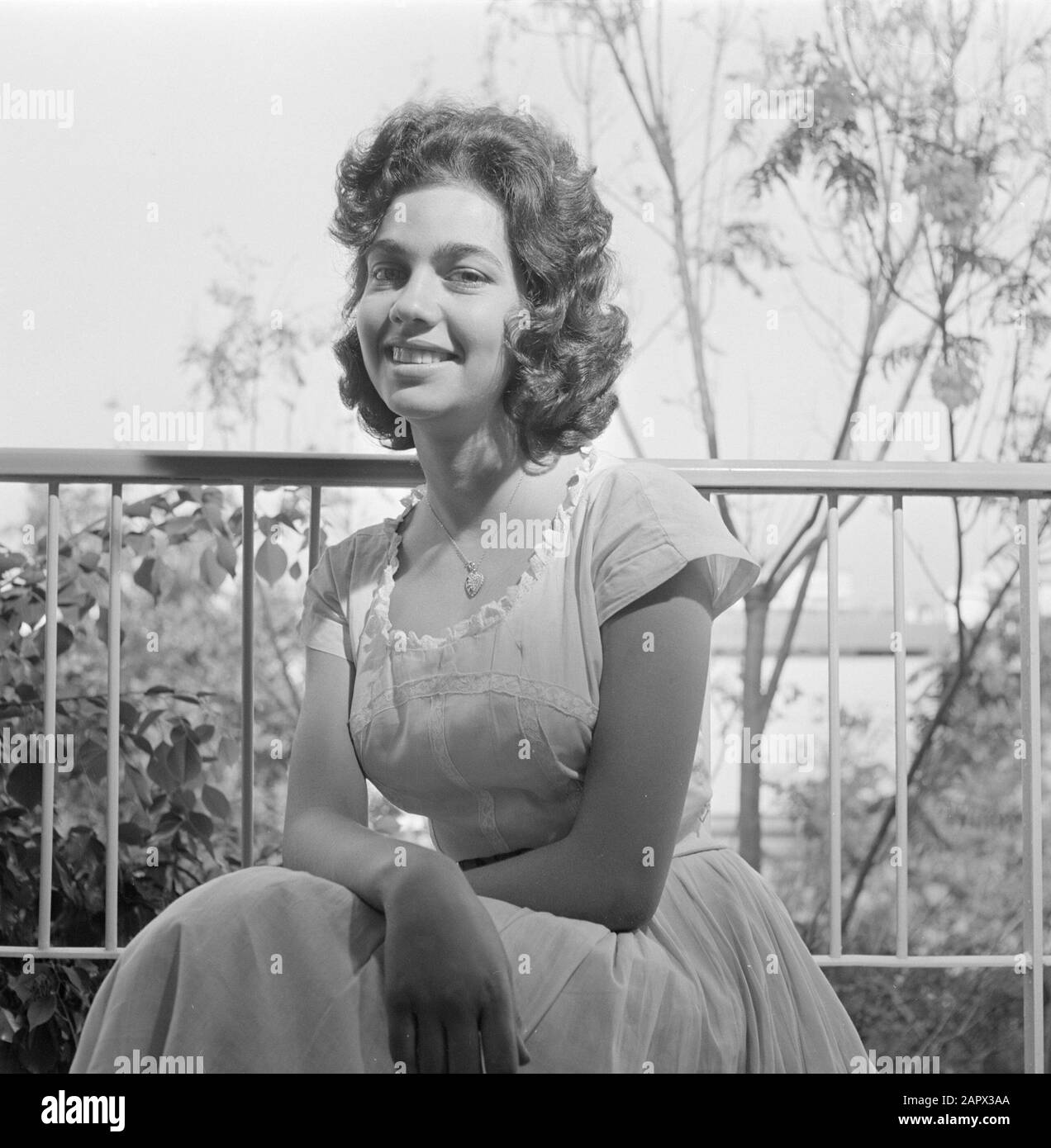 Portrait of Nurit Makover seated on the concrete edge of a balcony ...