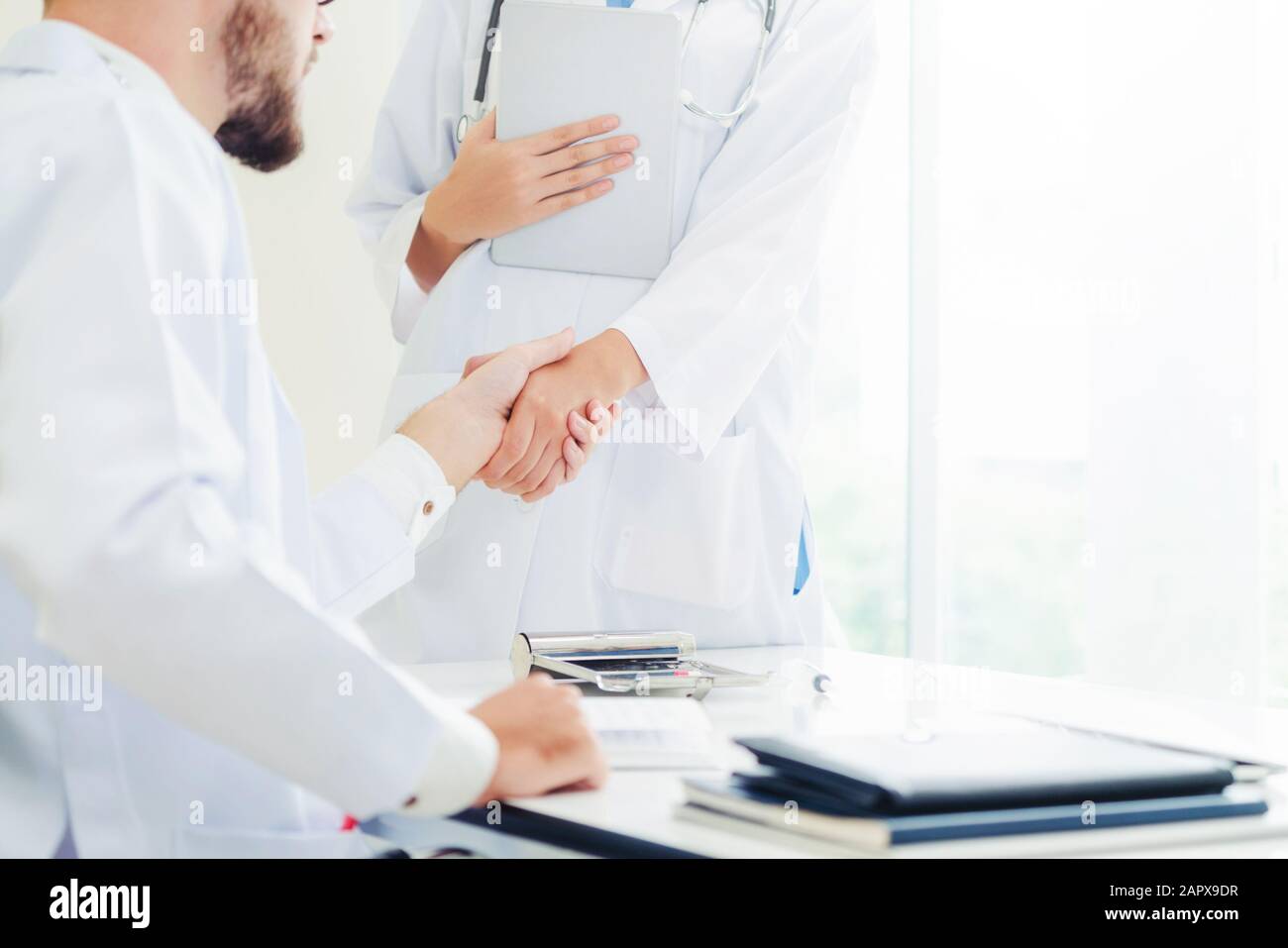 Doctor at the hospital giving handshake to another doctor showing ...