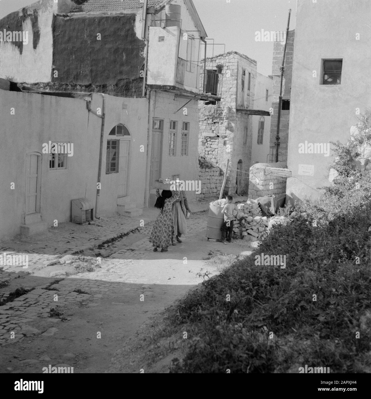 Streetscape in Safad (Safed). A man and a woman carrying a cardboard ...