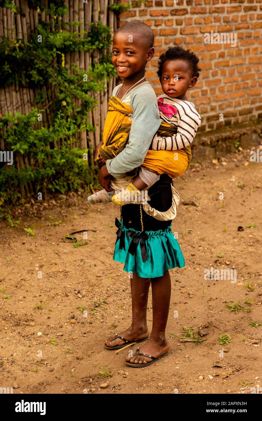 Laughing girl carries sibling on her back, Rubona, Rwanda Stock Photo ...