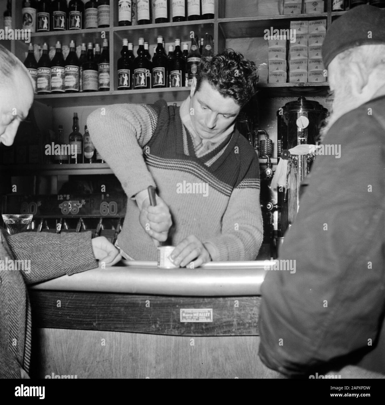 Two men visit a cafe Two men stand at the bar while the bartender opens ...