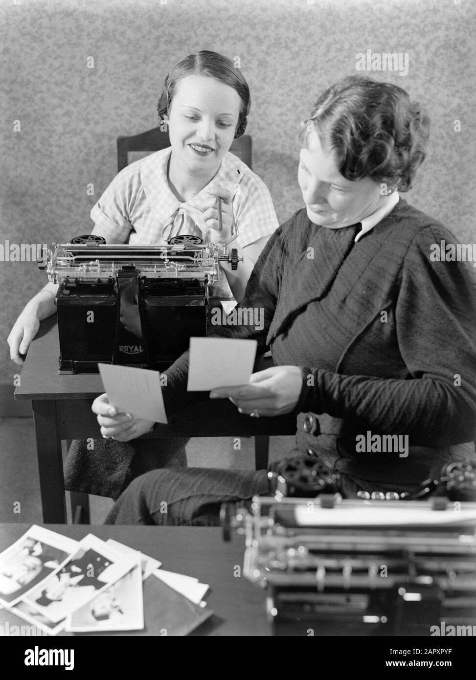 Two women with typewriters view photos Date: 1931 Keywords: typewriters ...