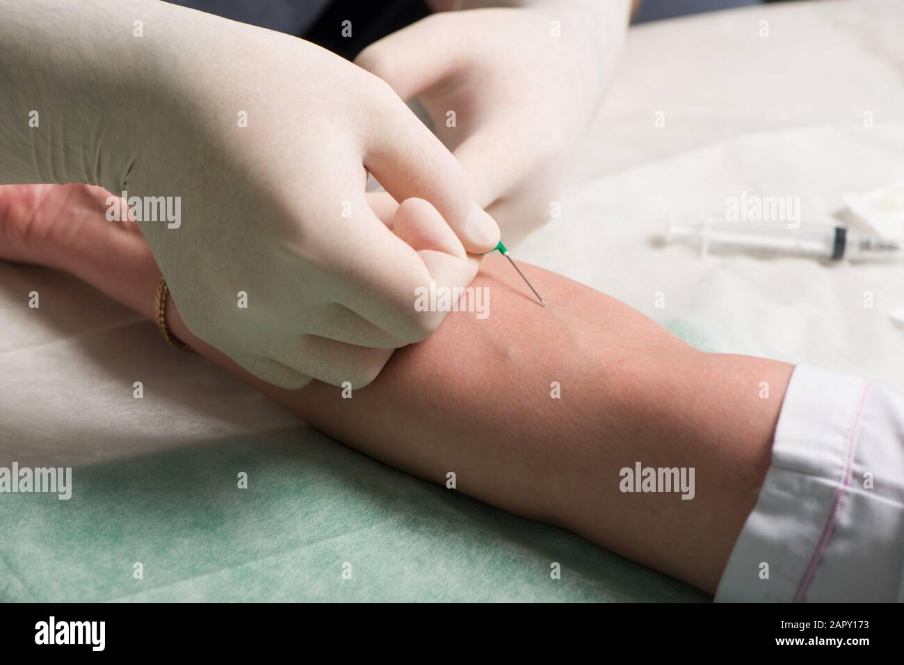 Hands in medical gloves perform vein puncture in area of ulnar bend of ...