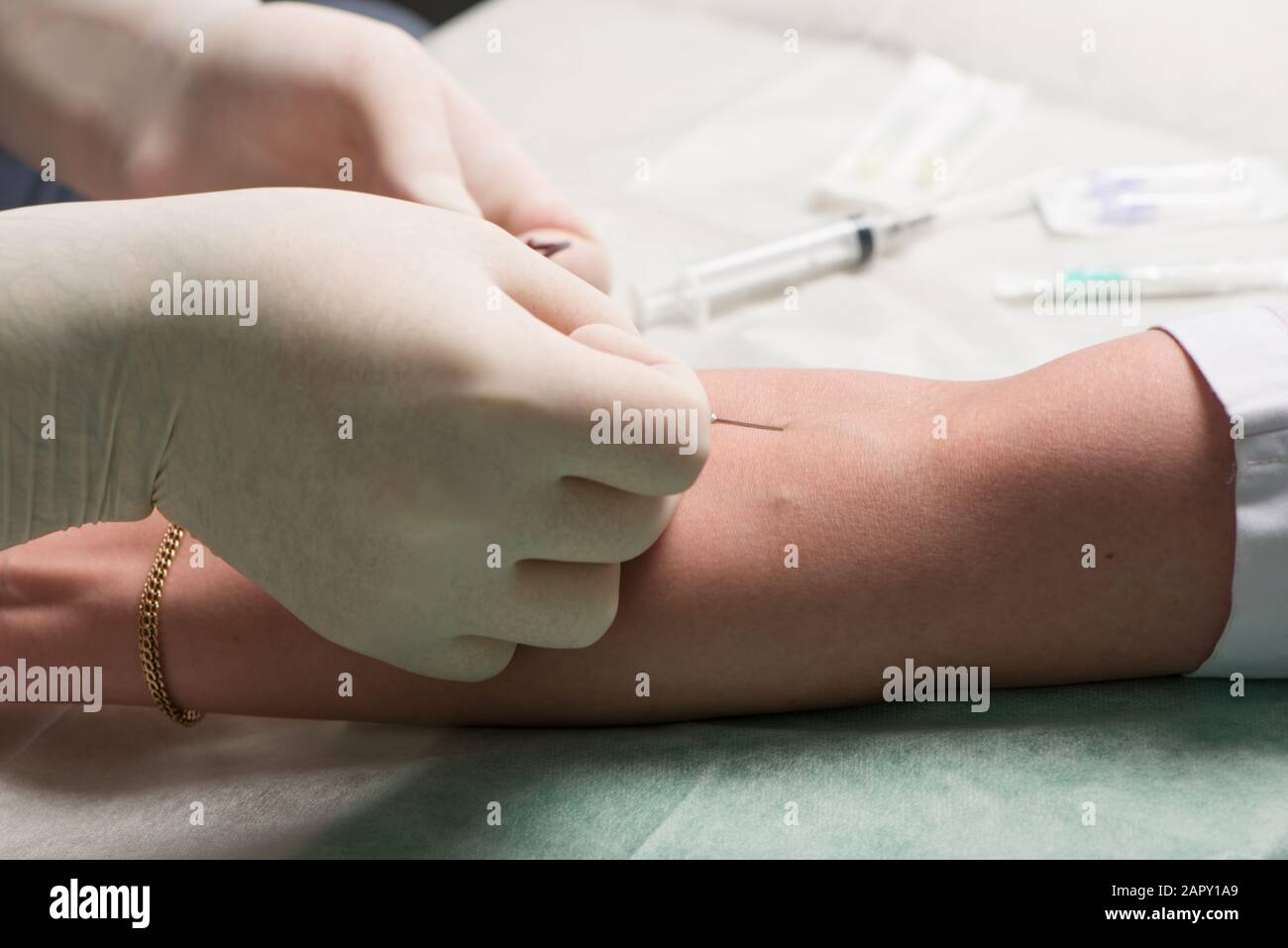 Hands in latex medical gloves perform vein puncture in ulnar bend of ...