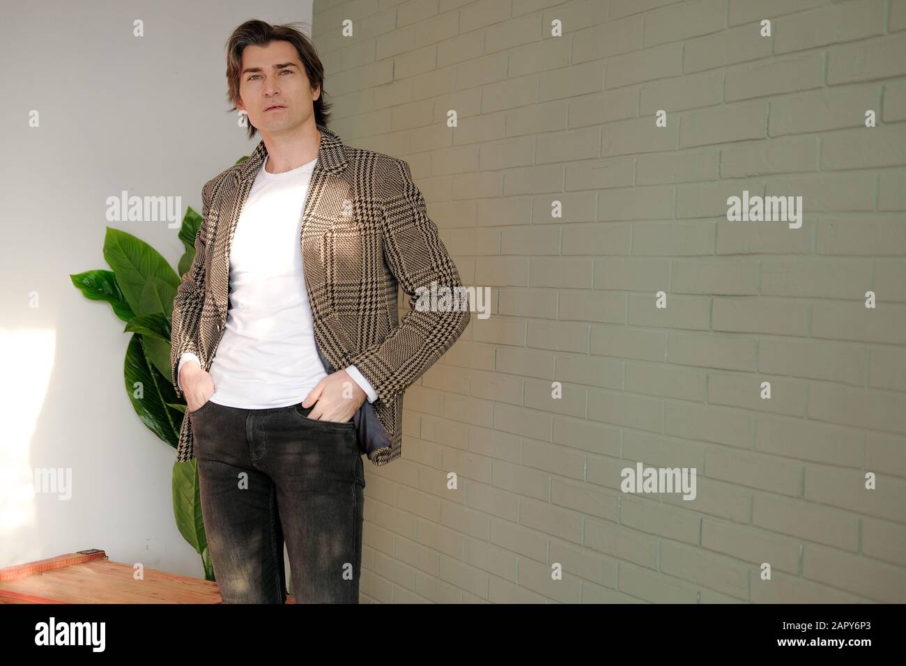 Tall handsome man standing next to grey wall Stock Photo - Alamy
