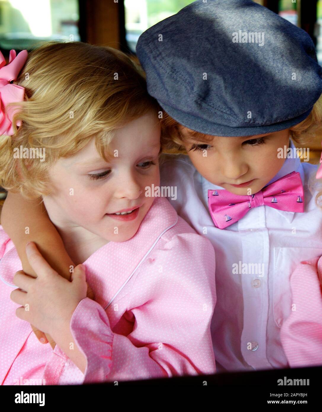 Vertical picture of two kids hugging each other under the sunlight with ...