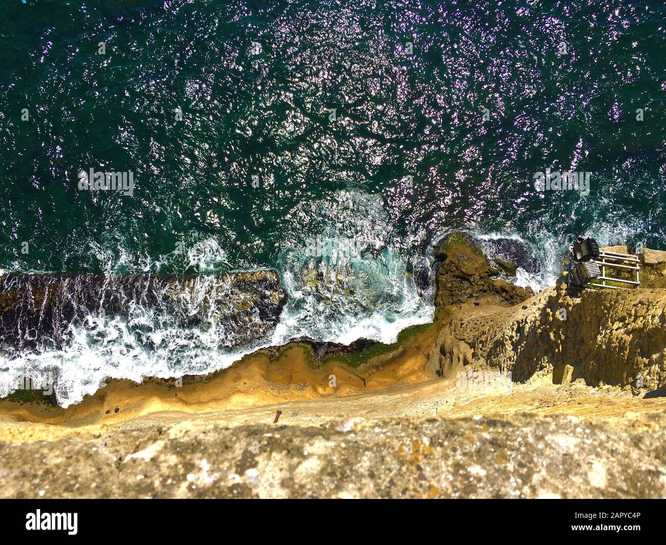 High angle shot from the top of the cliff with sea waves hitting on the ...