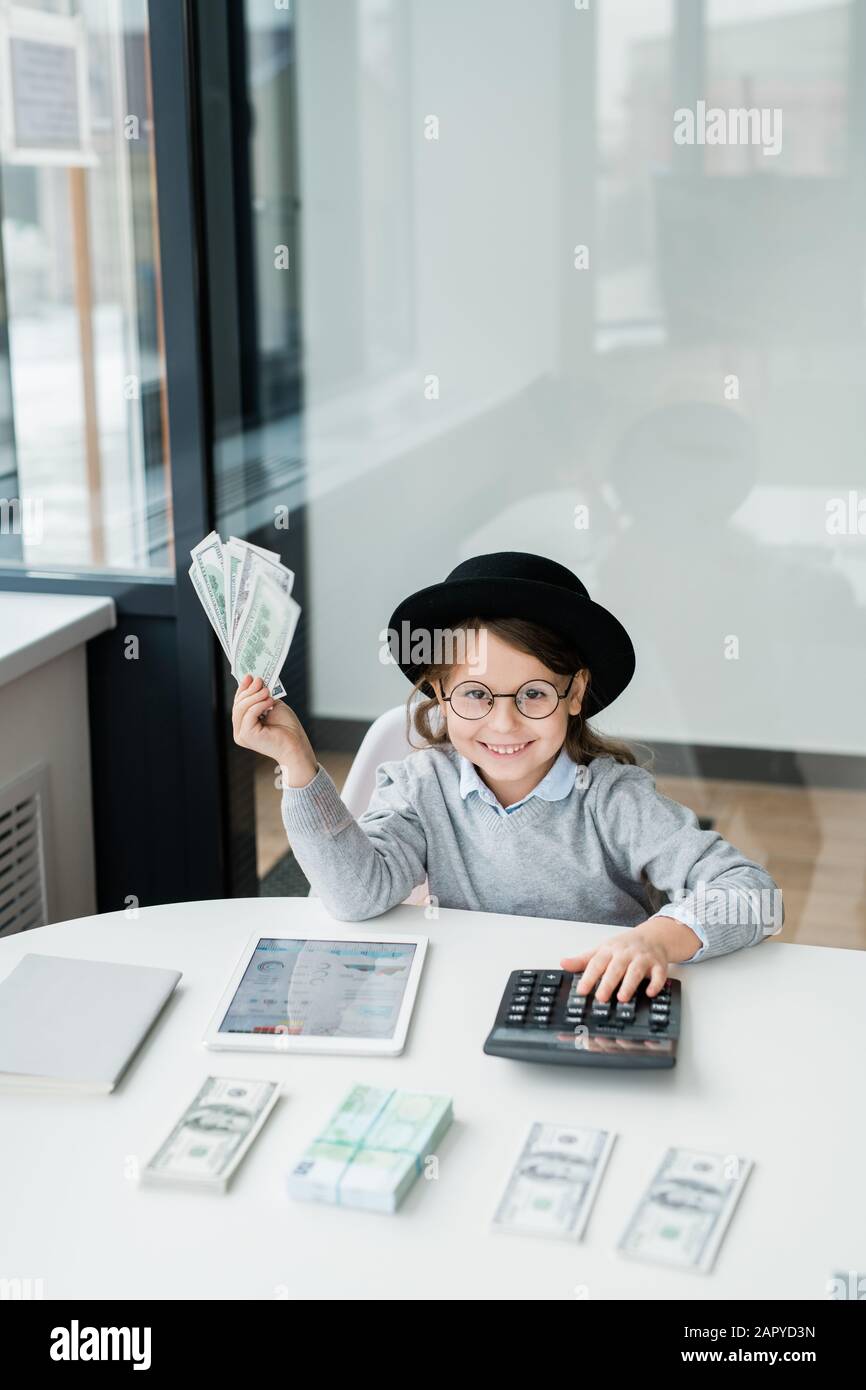 Little cheerful accountant in hat and casualwear counting your salary ...