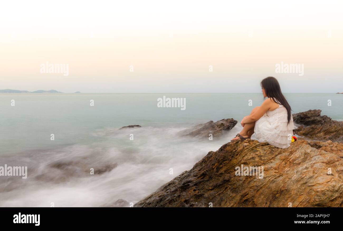 A sad and depressed woman sitting by the ocean deep in thought Stock ...
