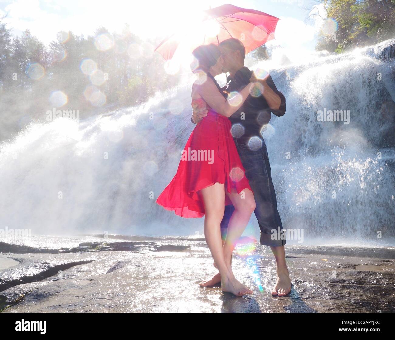 Couple kissing and dancing in a park with a waterfall on the background ...