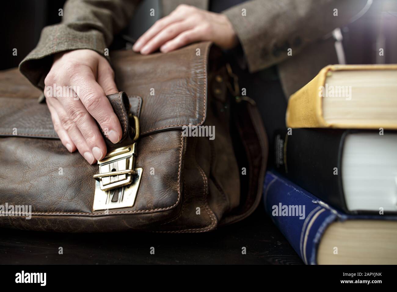 Hand fastens a buckle on an old brown, classic, leather briefcase ...
