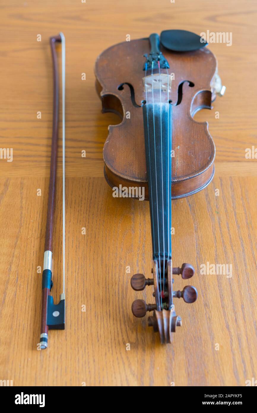 violin lying on a wooden textured table. Violin body and bow on wood ...