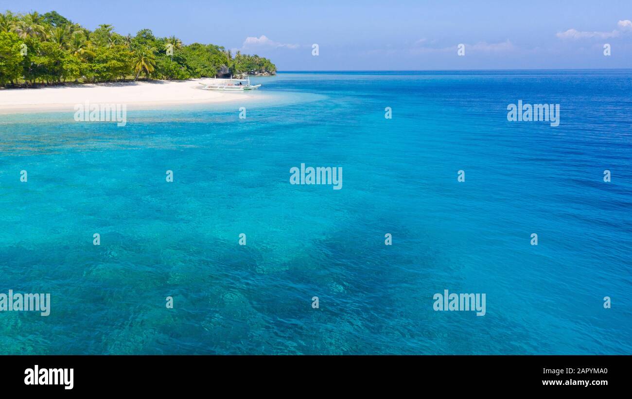 Turquoise lagoon and tropical island. An island with palm trees in an ...