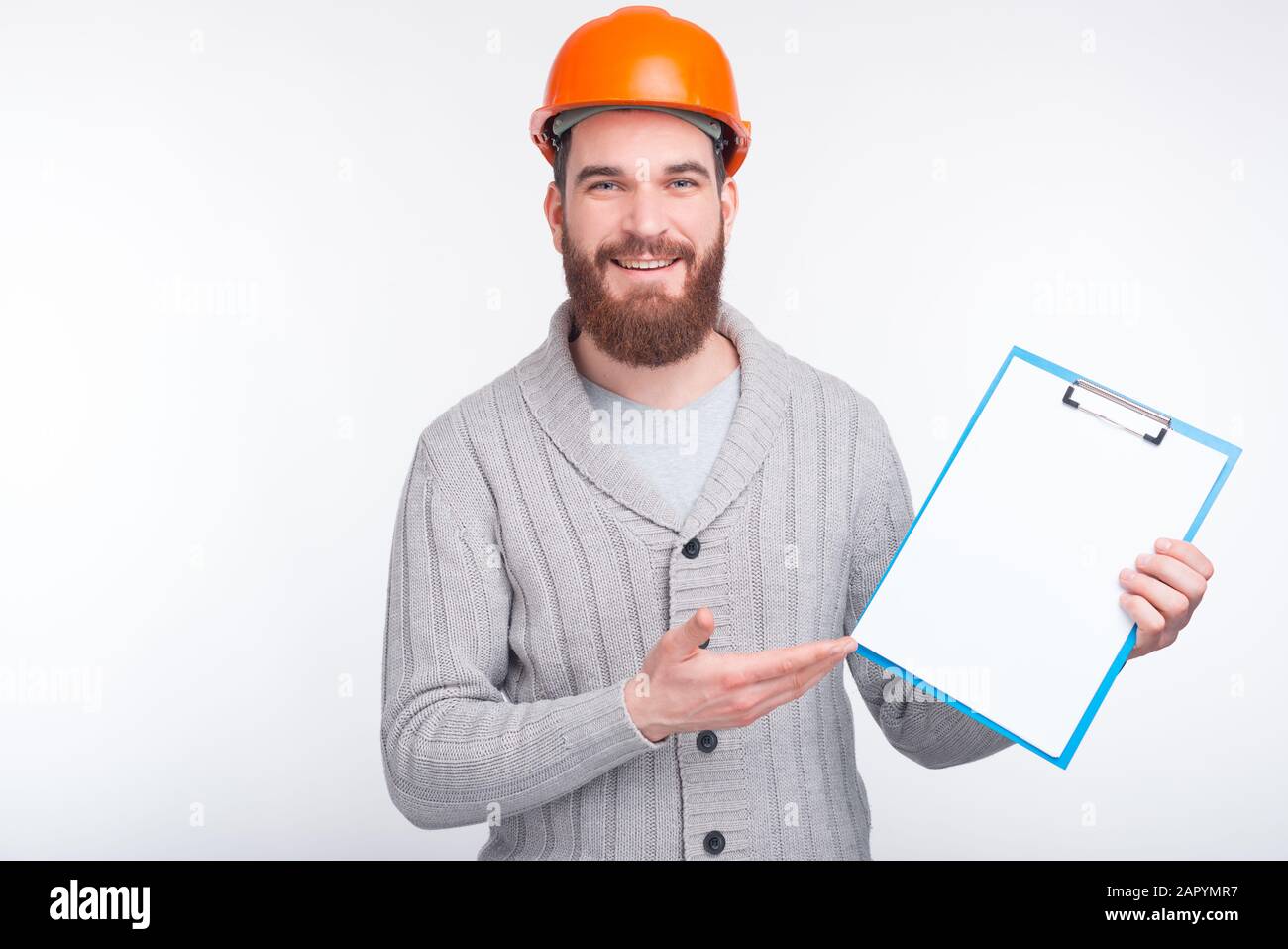 A constructor smiling and pointing at a paper holder near white ...
