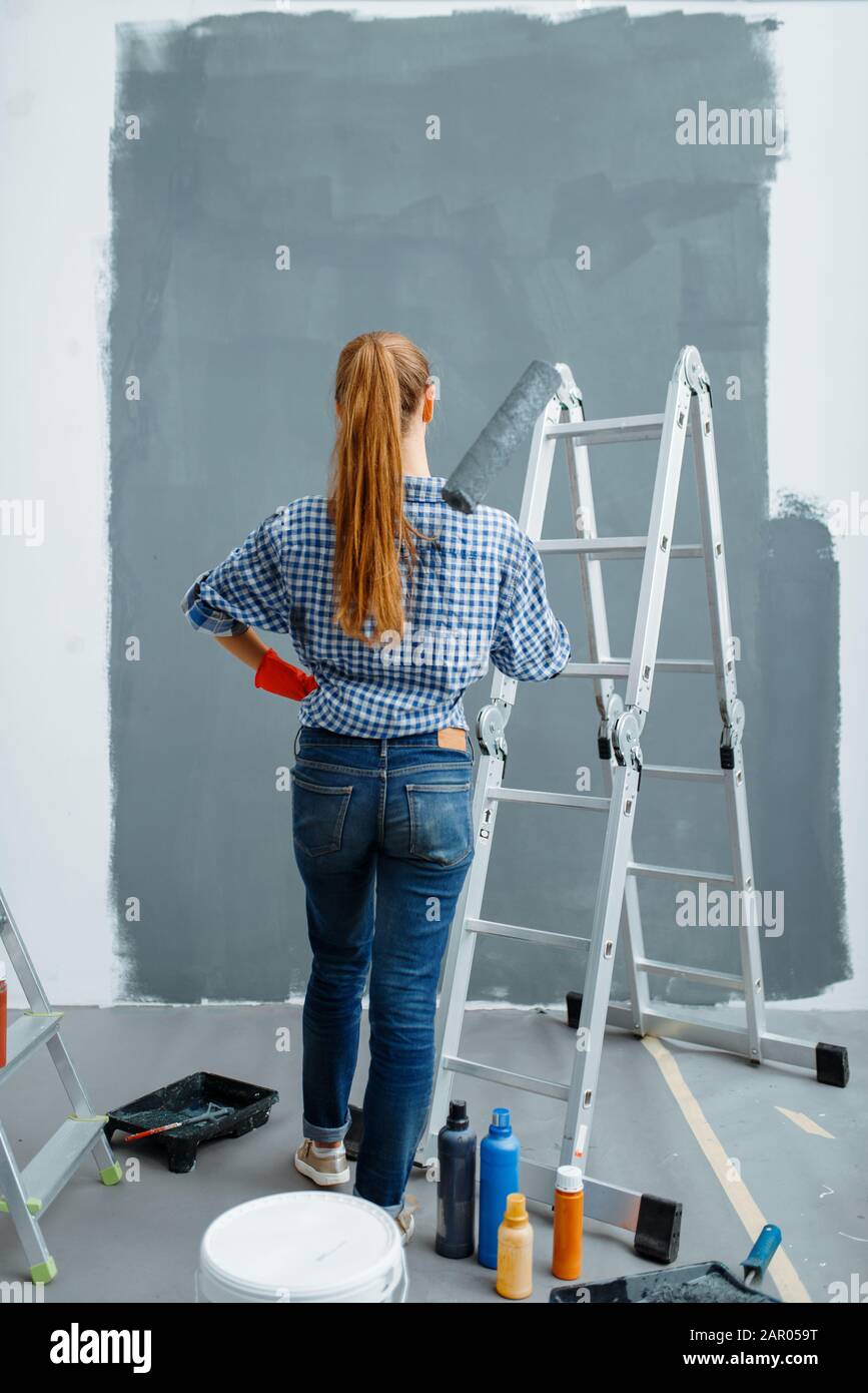 Female house painter looking on wall, back view Stock Photo - Alamy