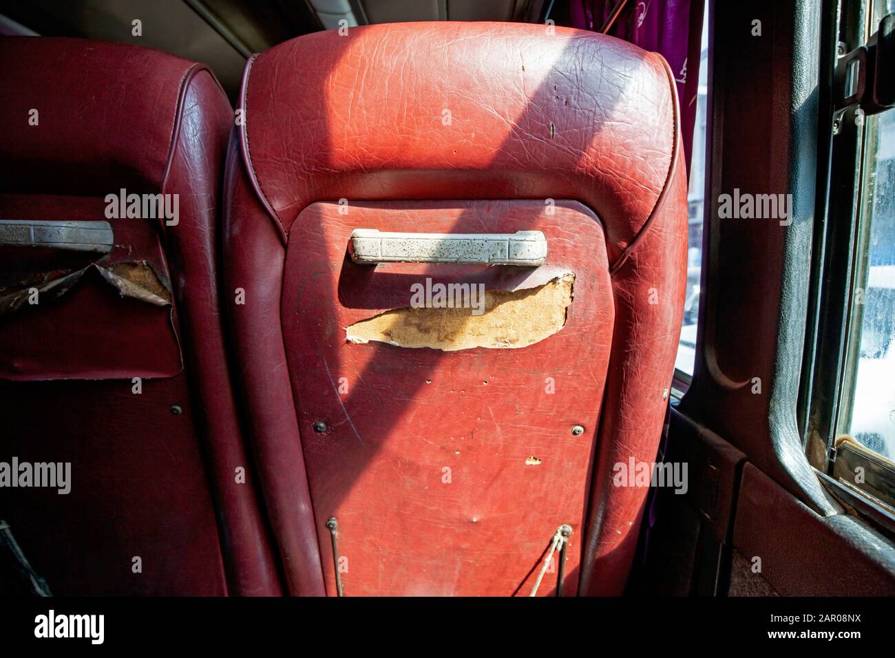 A dilapidated bus seat is empty on a poorly maintained bus operated by ...