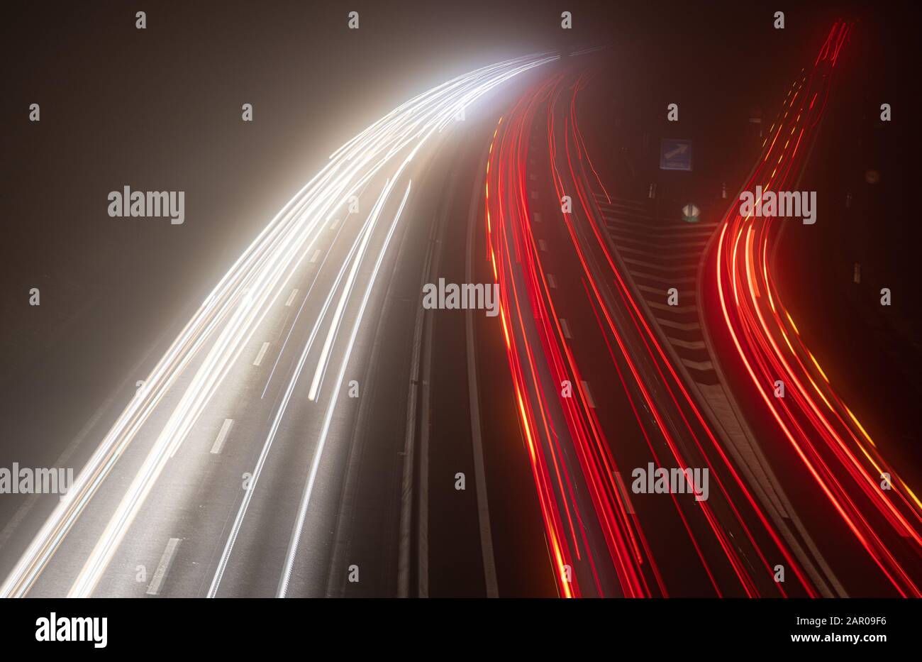 Highway at foggy night with bright trails of light from incoming and ...