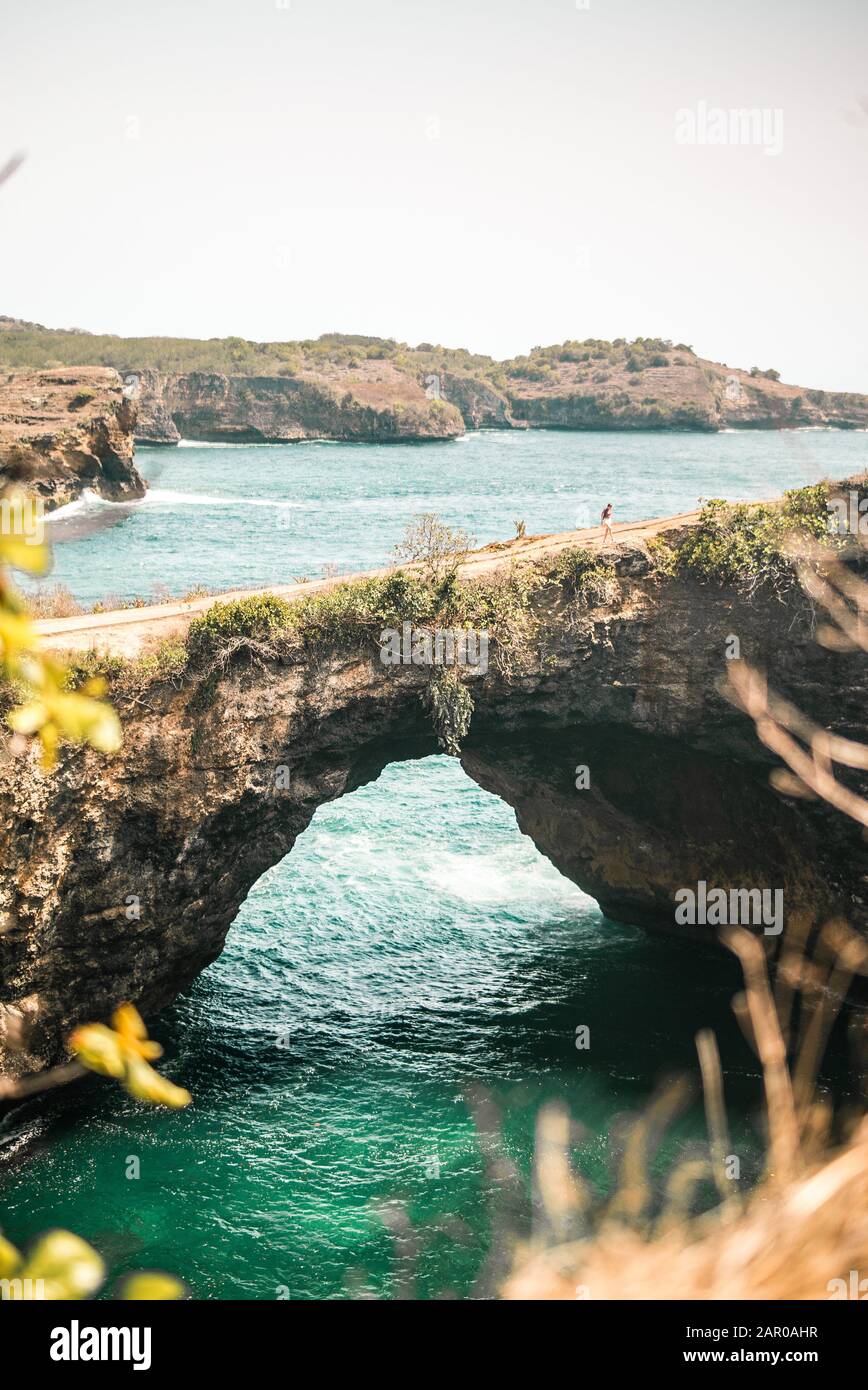 Single female on top of a big cliff with water around Stock Photo - Alamy