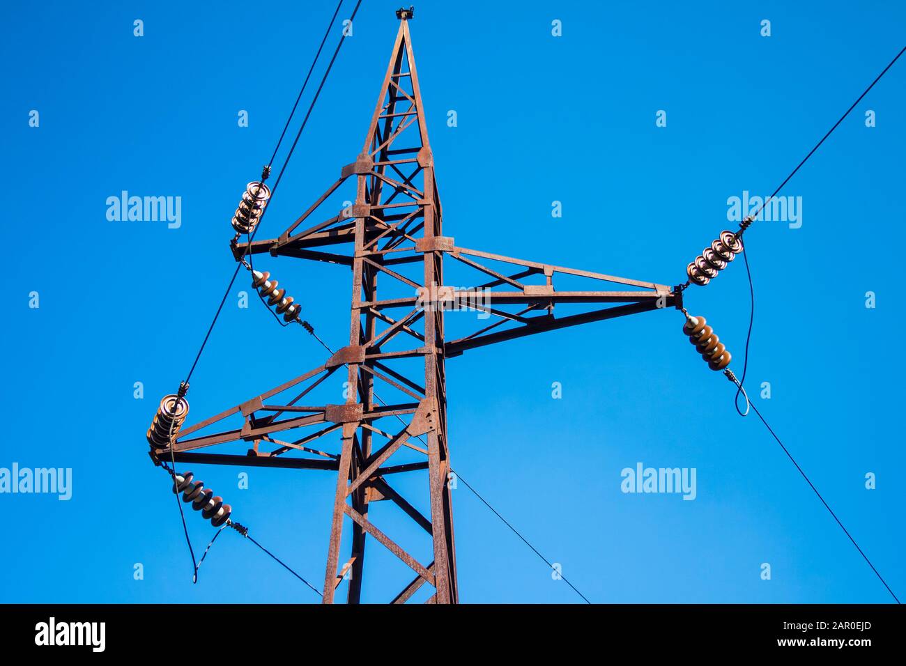Old rusty high voltage pole against blue sky background Stock Photo - Alamy