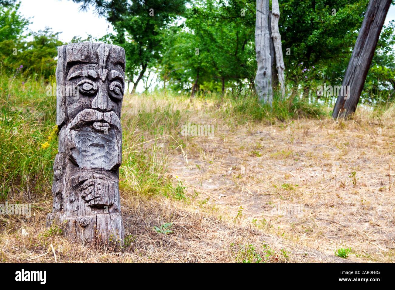 Wooden idol of Slavic god by a path in the forest. Forest in the ...