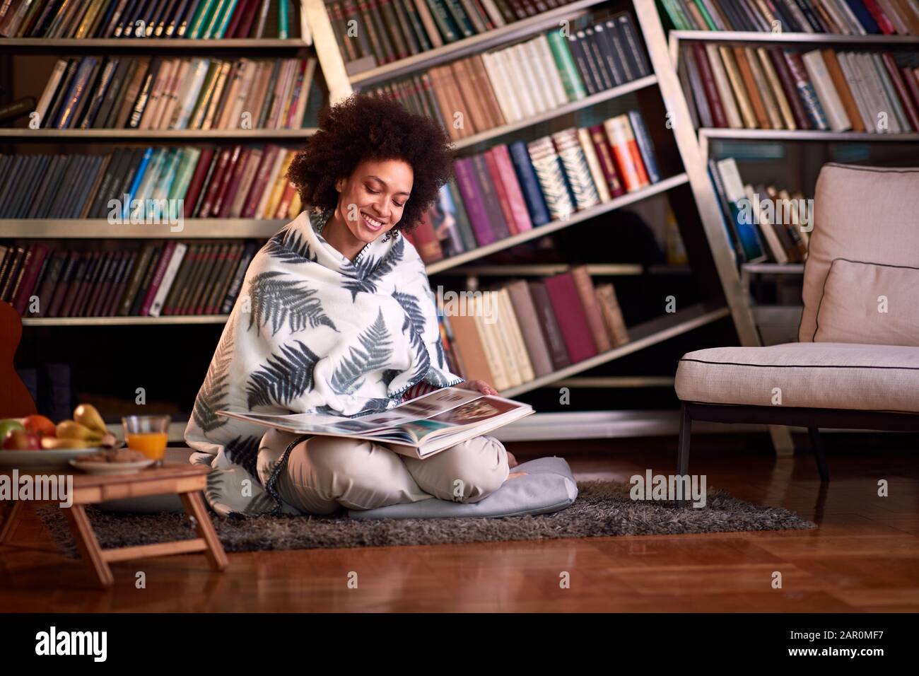 Female in home library sitting on the floor and looking in book Stock ...