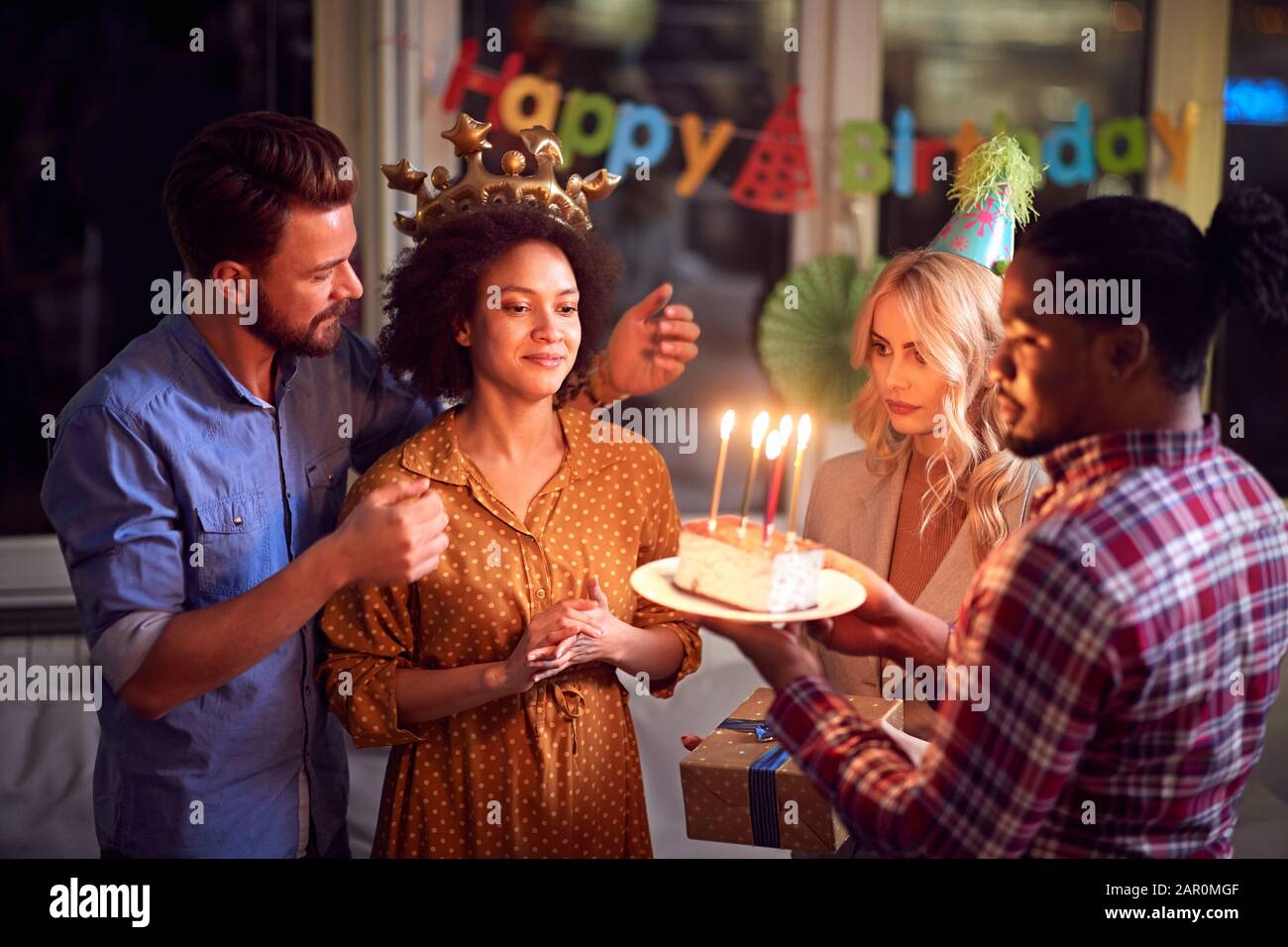 Cheerful friends giving birthday cake to birthday girl Stock Photo - Alamy