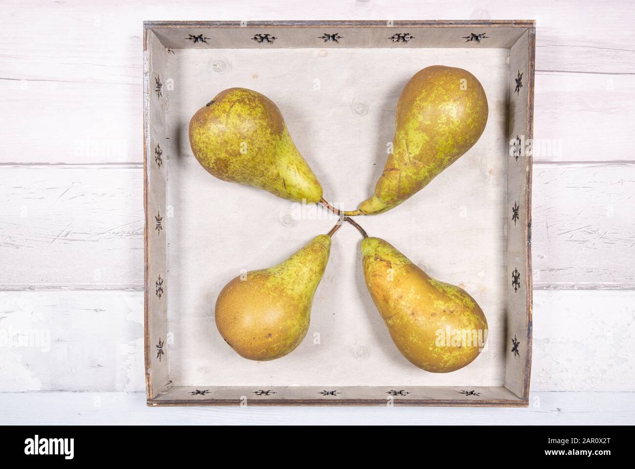 four conference pears placed in an old wooden tray on an old wooden ...