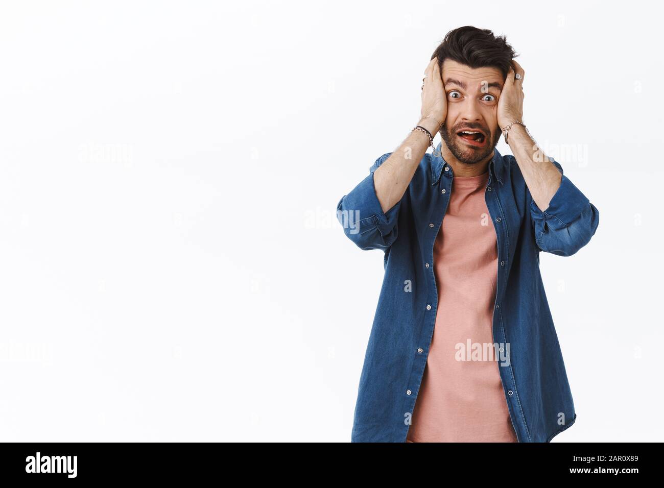 Shocked freak-out, alarmed young bearded guy, scream in panic grab head ...