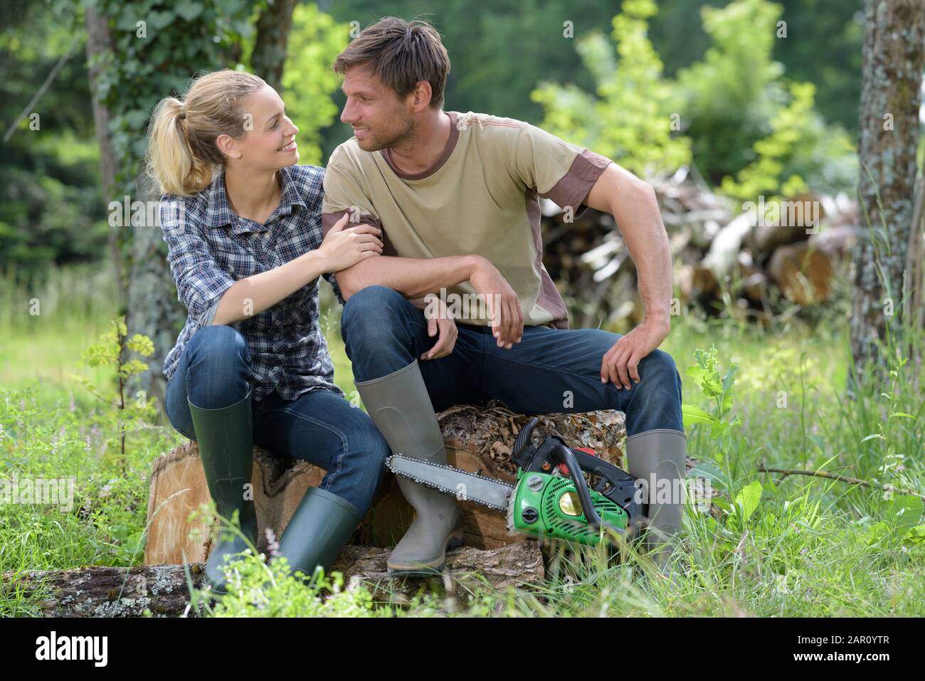 couple with chainsaw in the woods taking a break Stock Photo - Alamy