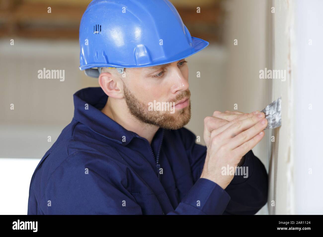 male builder smoothing filler on to wall Stock Photo - Alamy