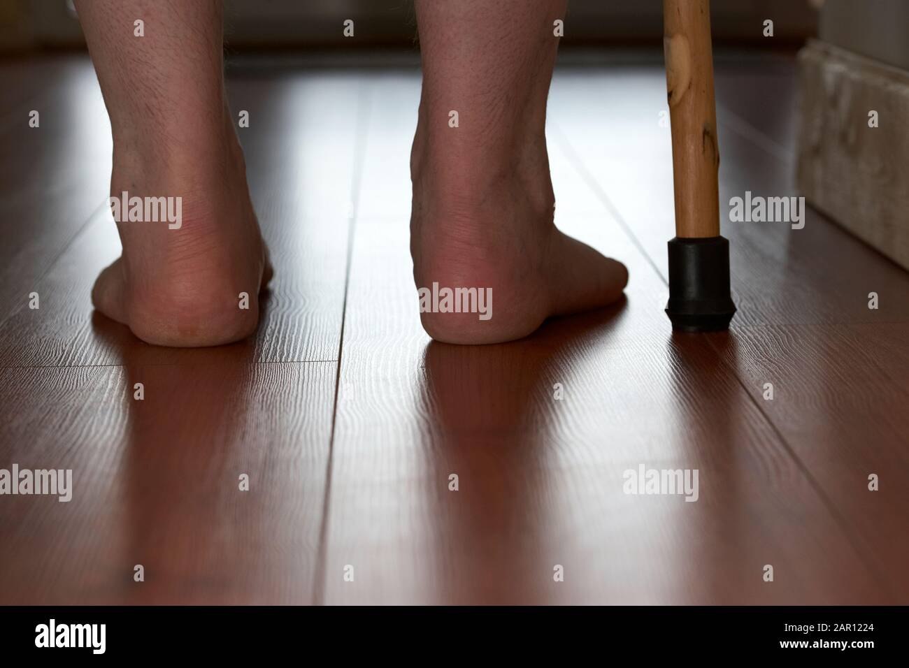 disabled middle aged man walking indoors on laminate flooring with ...
