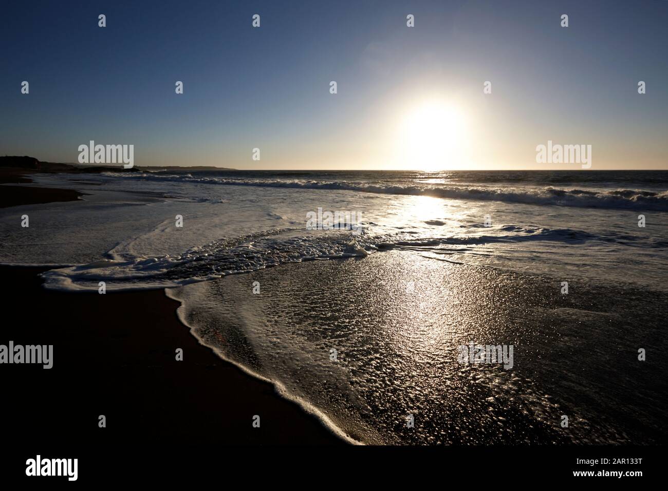 sun setting over sandy beach on the pacific ocean los pellines maule ...